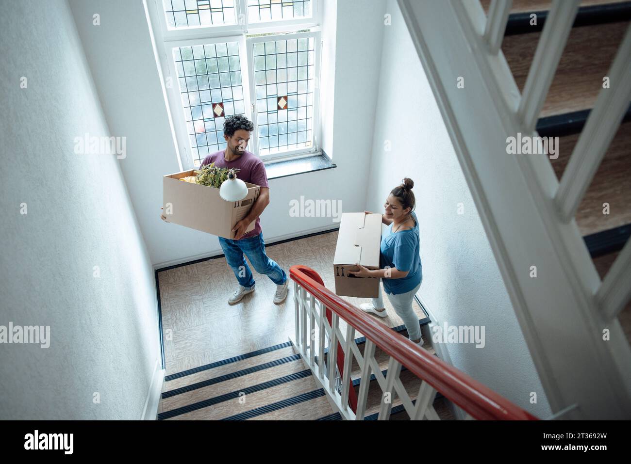 Happy man and woman with cardboard boxes moving up on staircase Stock ...