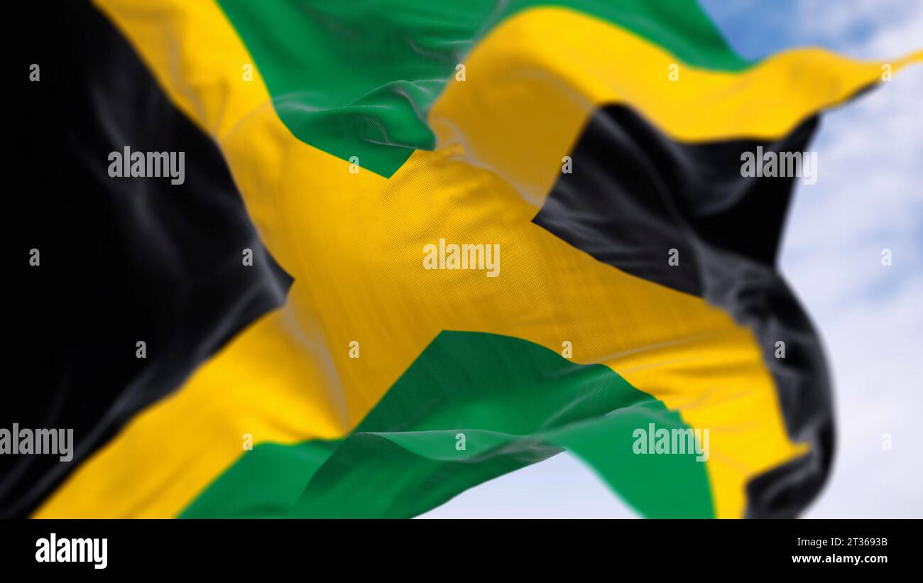 Close-up of Jamaica national flag waving on a clear day. Gold saltire ...