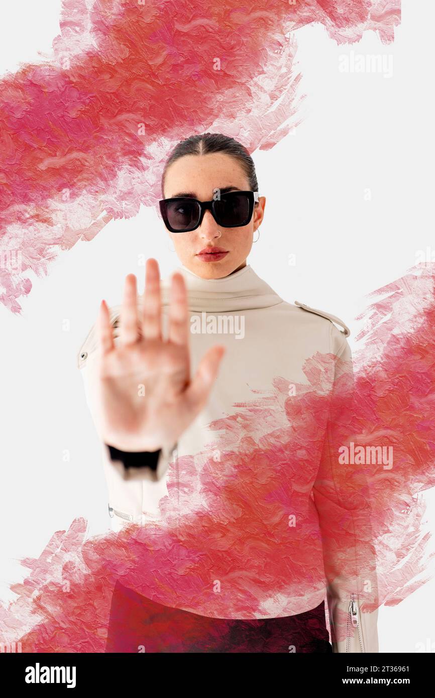 Woman wearing sunglasses showing stop sign in front of wall Stock Photo ...