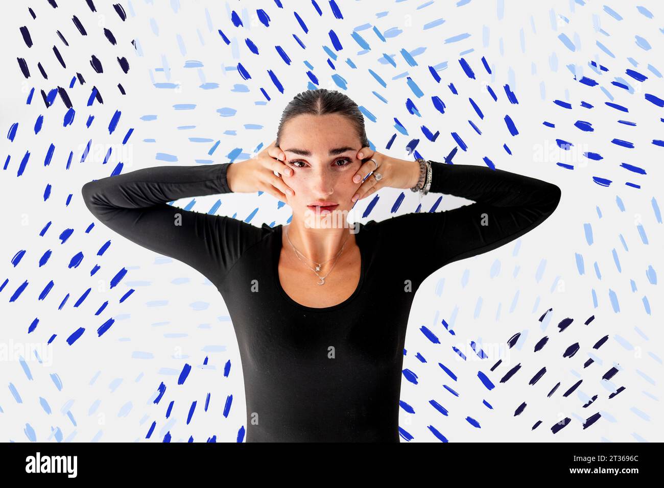 Beautiful woman touching cheeks in front of wall Stock Photo - Alamy