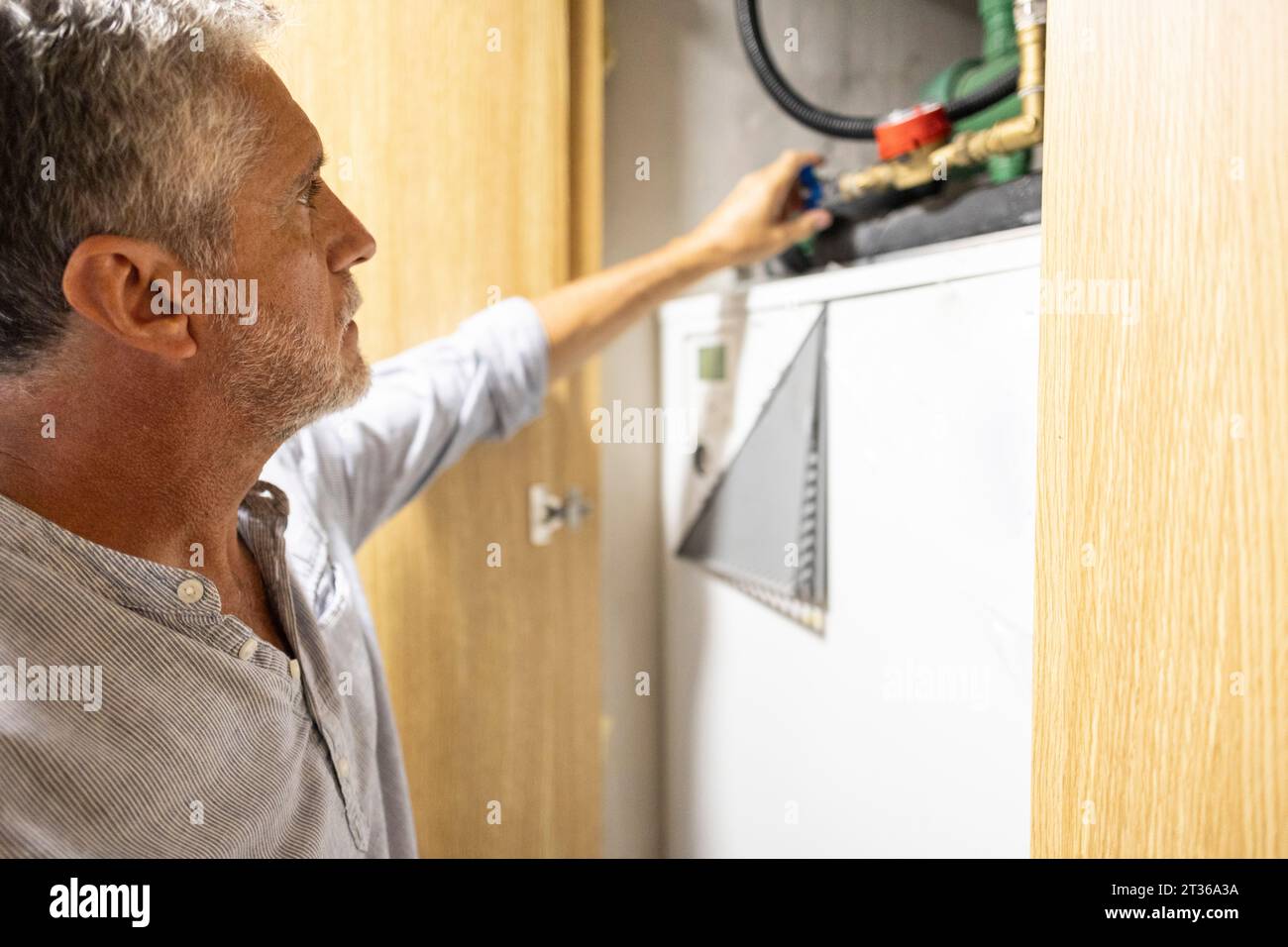 Man turning on valve at home Stock Photo - Alamy