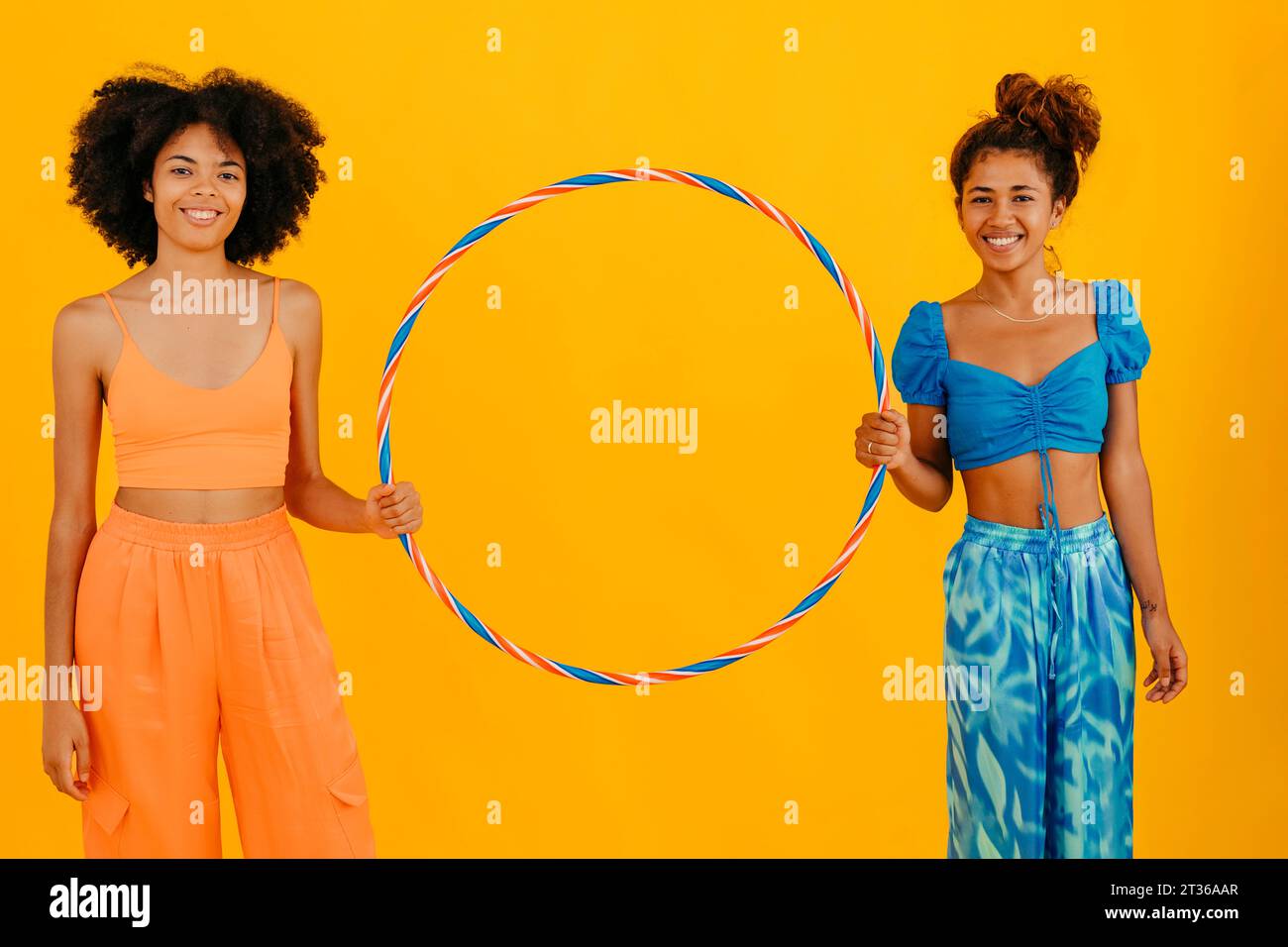 Smiling multiracial friends holding plastic hoop standing against ...