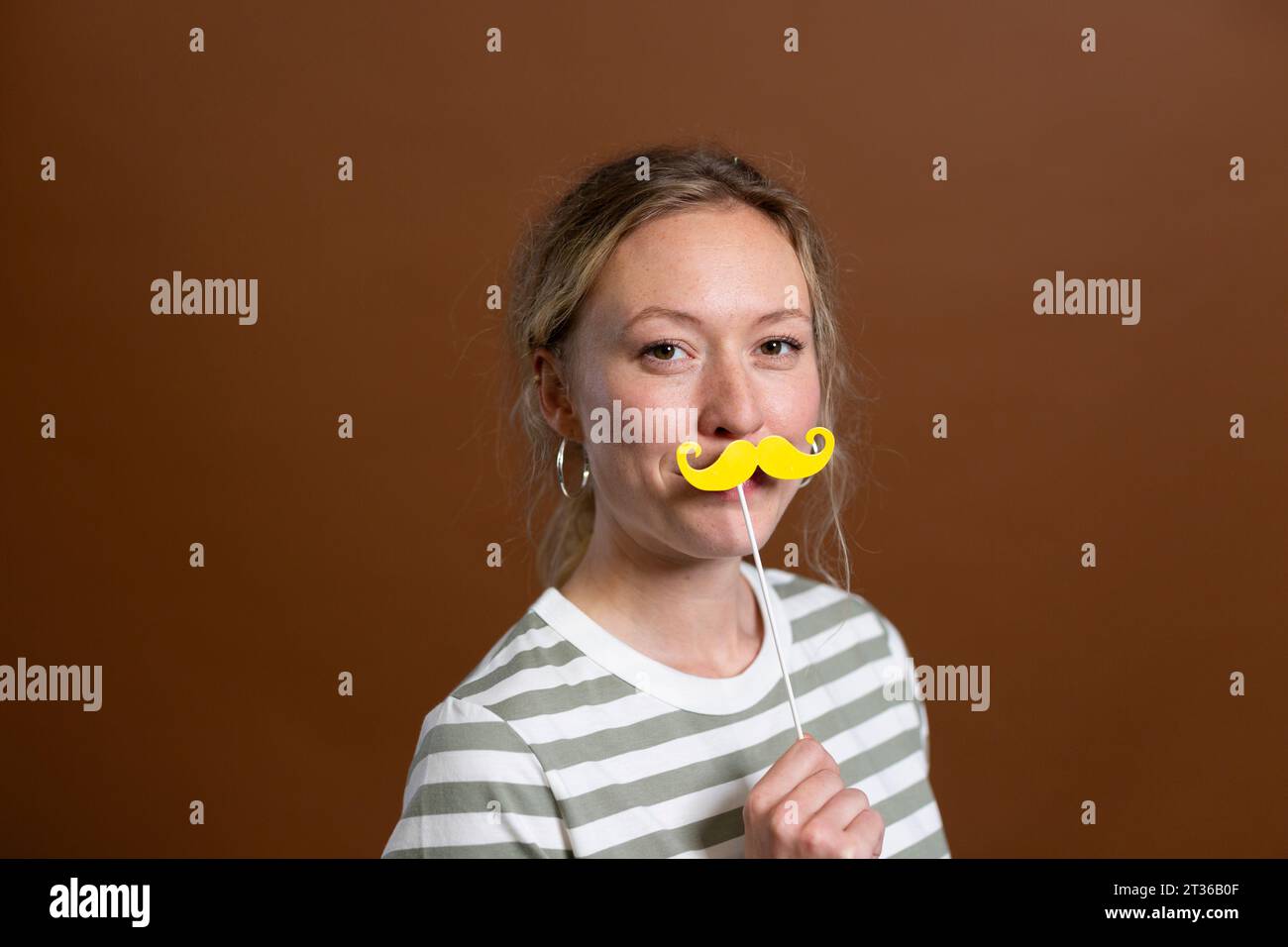 Blond woman holding mustache prop in studio Stock Photo - Alamy