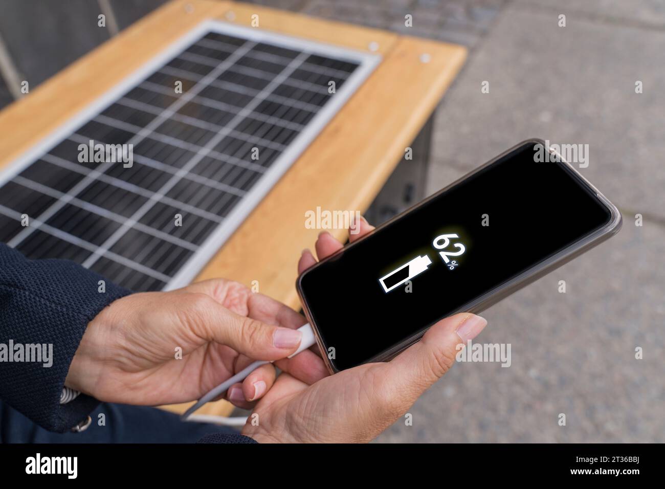 Hands of businesswoman charging smart phone using solar power on bench ...