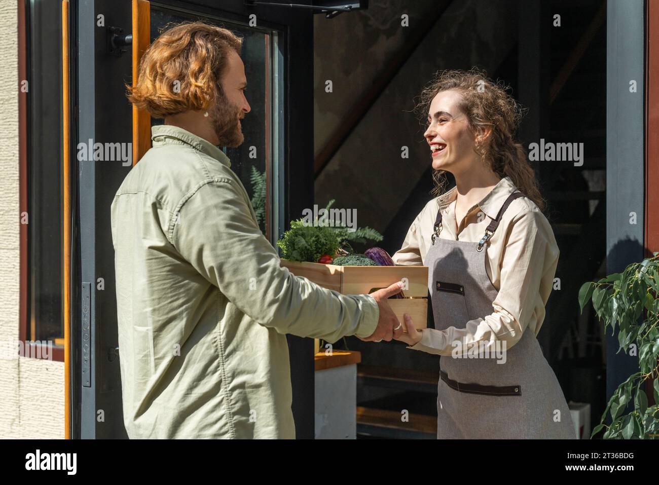 Customer receiving vegetable crate from happy owner at store Stock ...