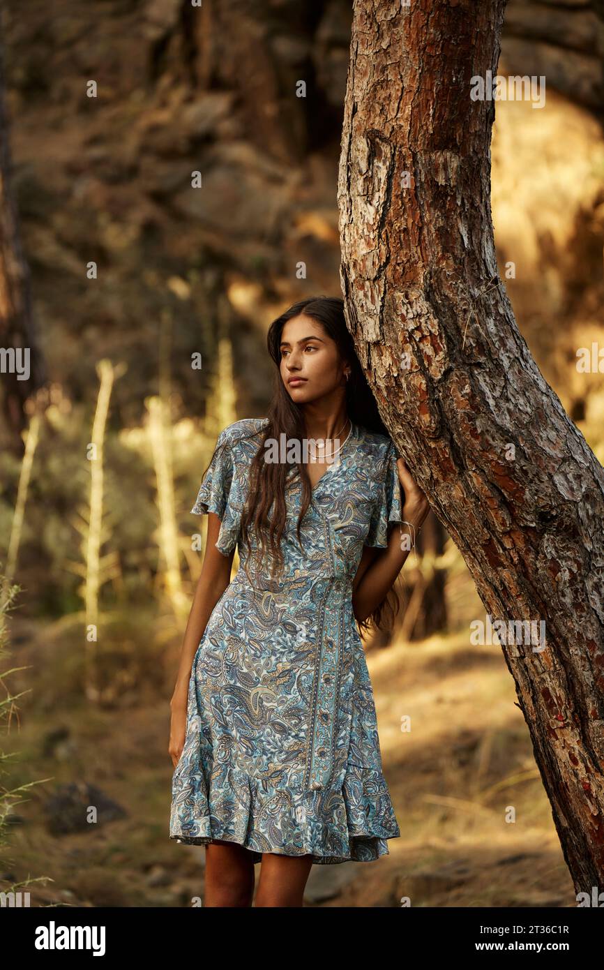 Teenage girl leaning on tree trunk in forest Stock Photo - Alamy