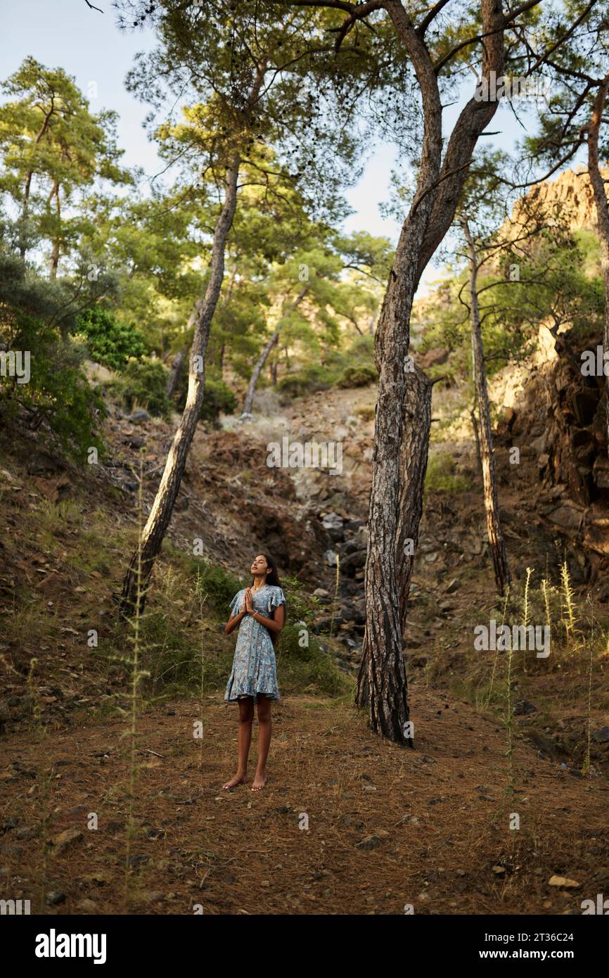 Teenage girl standing near trees in forest at sunset Stock Photo - Alamy