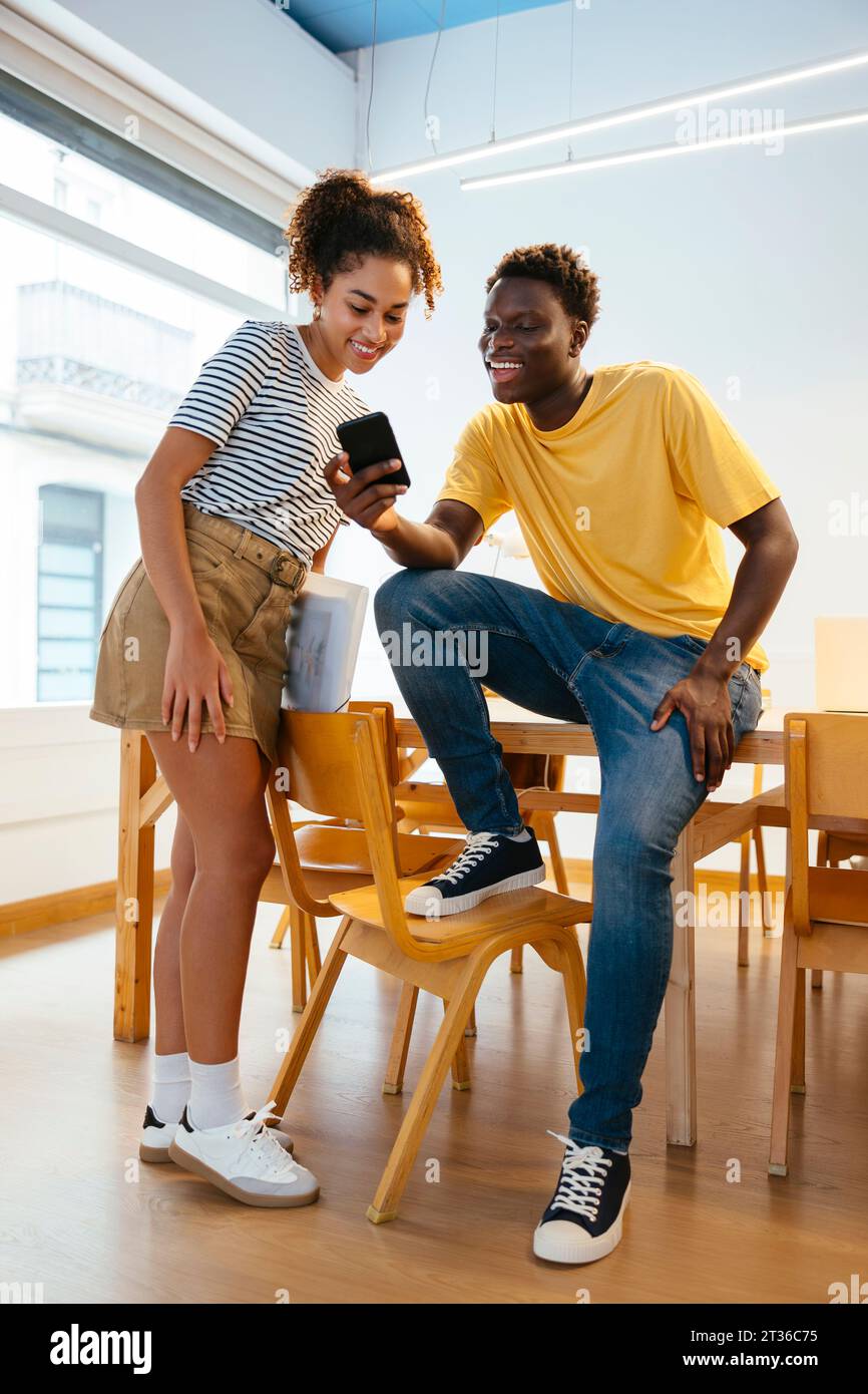 Happy students using mobile phone at university Stock Photo - Alamy