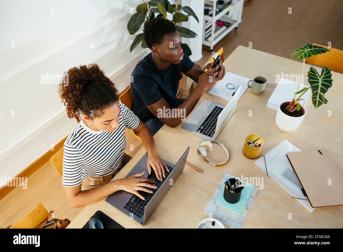 Young students using laptop and smart phone at desk Stock Photo - Alamy