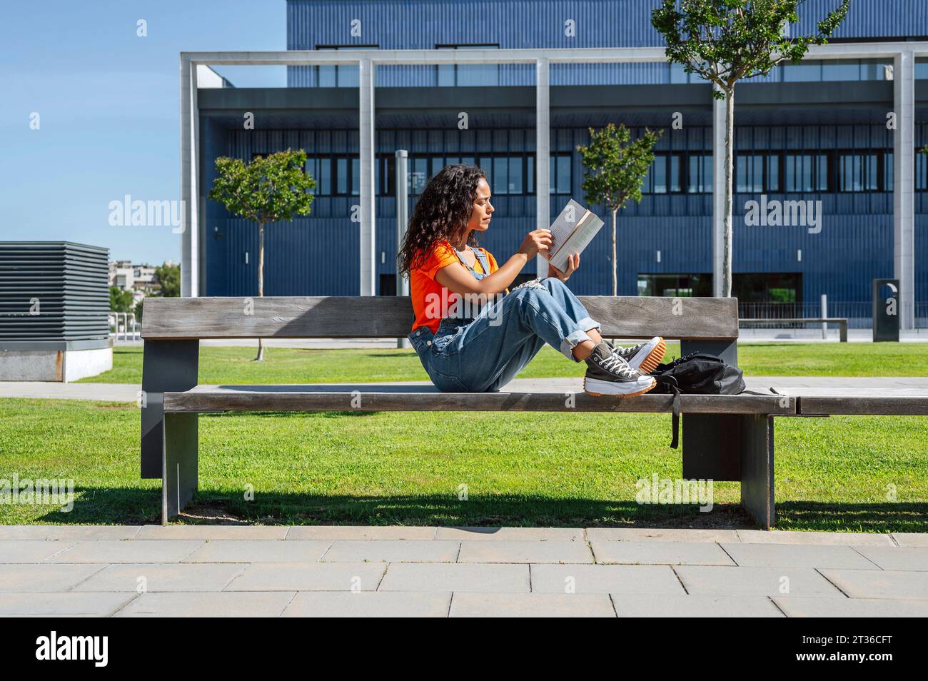 Young student sitting on bench and studying in front of building Stock ...
