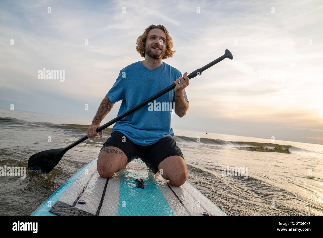 Happy man paddleboarding in sea at beach Stock Photo - Alamy
