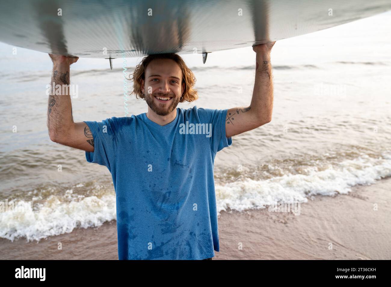 Happy man carrying paddleboard near sea at beach Stock Photo - Alamy