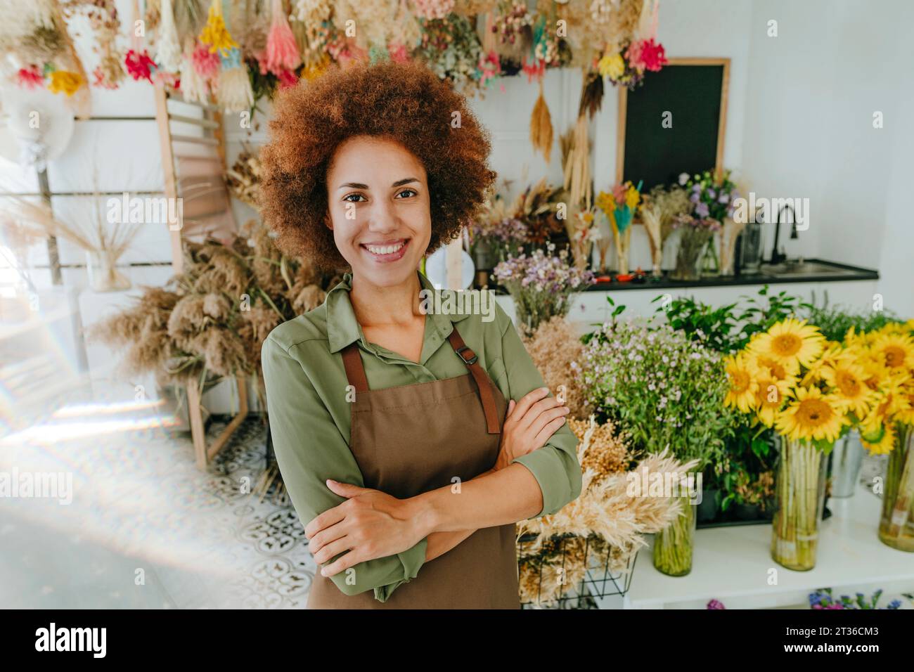 Smiling florist with arms crossed at flower shop Stock Photo - Alamy