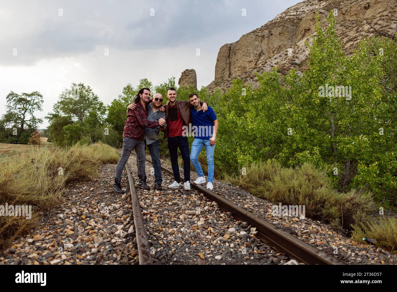 Happy friends standing on railroad tracks amidst plants Stock Photo - Alamy