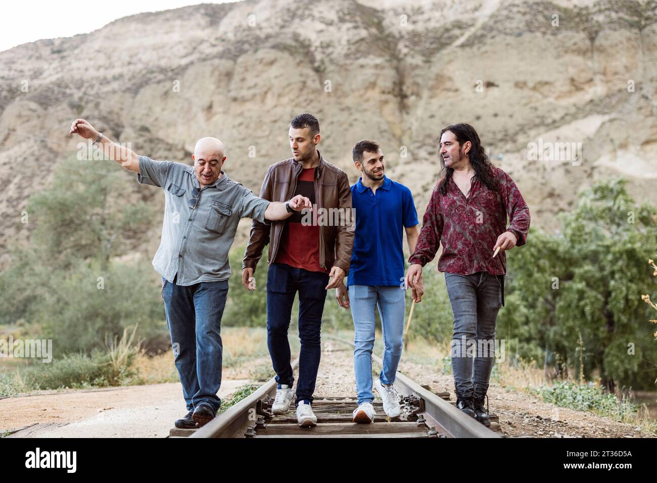 Friends walking on railroad tracks amidst plants Stock Photo - Alamy