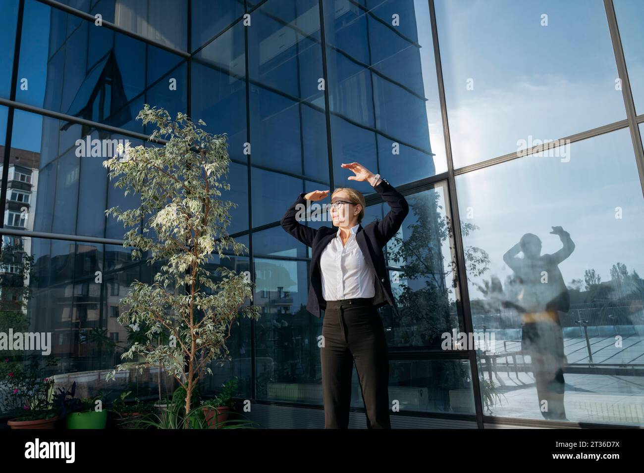 Businesswoman shielding eyes on terrace of business center Stock Photo ...