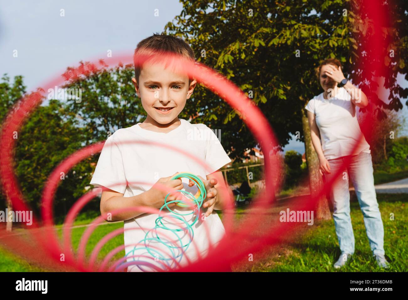 Boy holding spring toy with mother in background at park Stock Photo ...