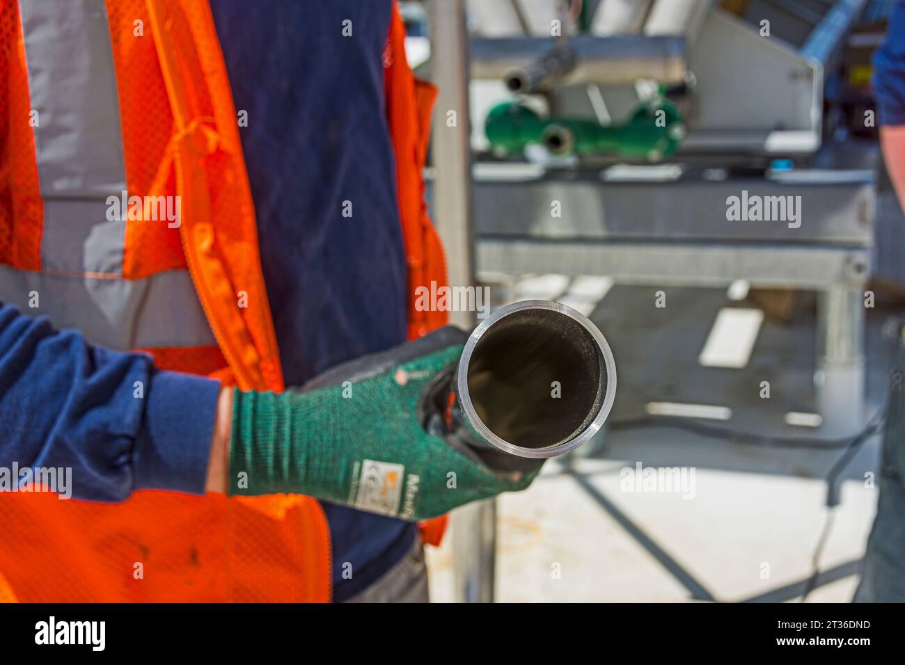 A worker shows the end of a length of stainless steel pipe that has ...