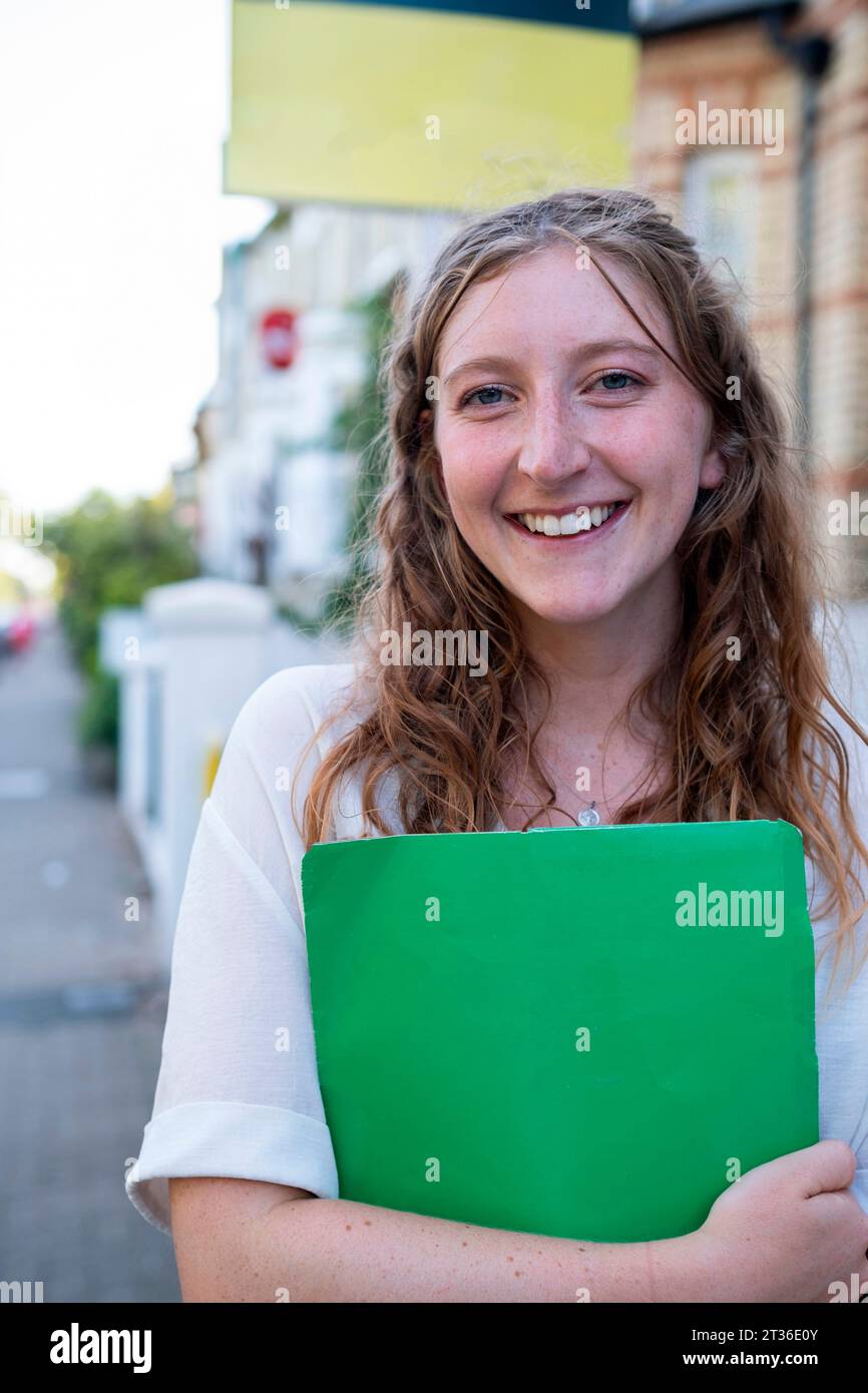 Happy real estate agent with long hair holding file folder Stock Photo ...