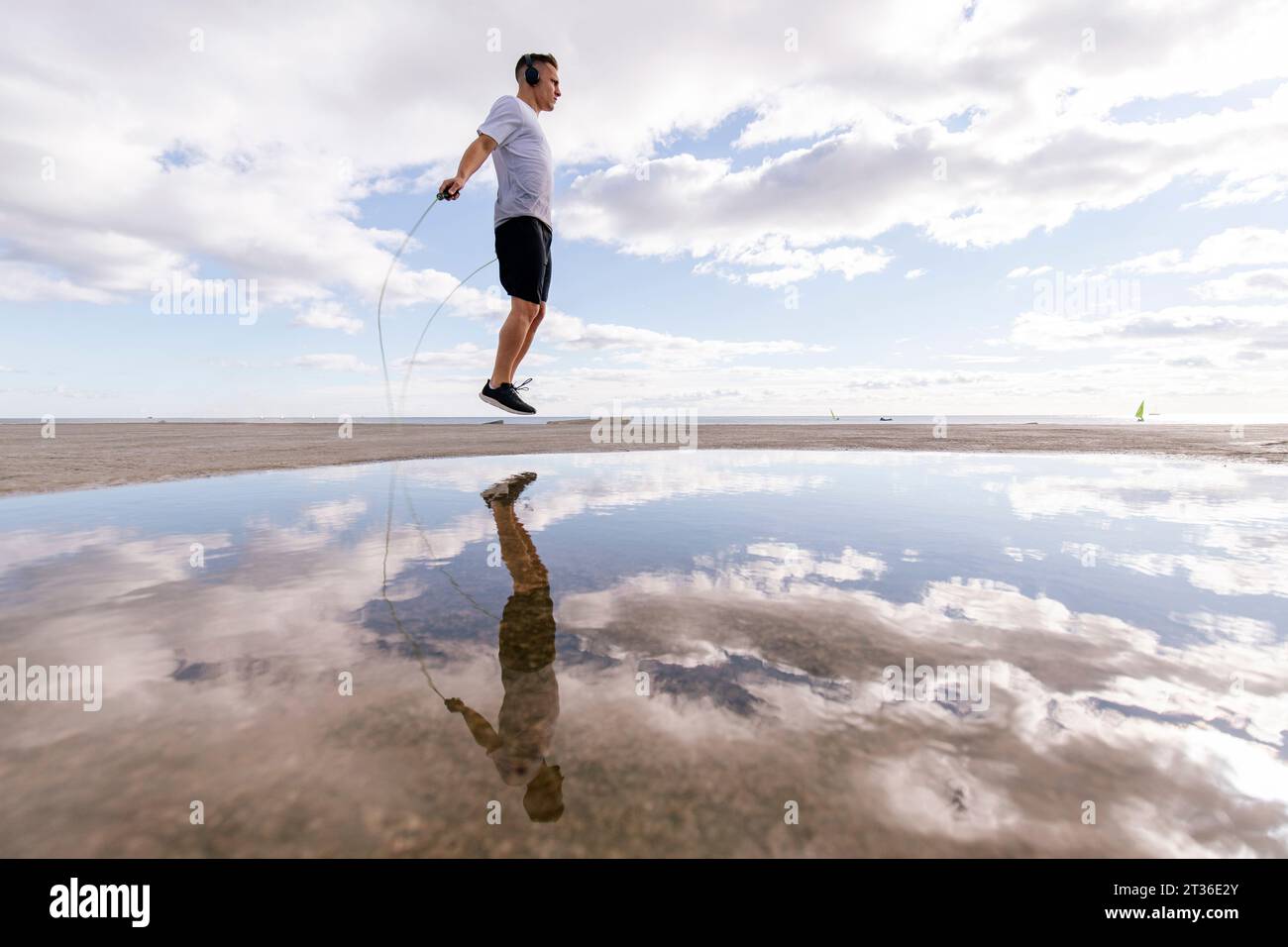 Young man jumping rope near puddle on pier Stock Photo - Alamy