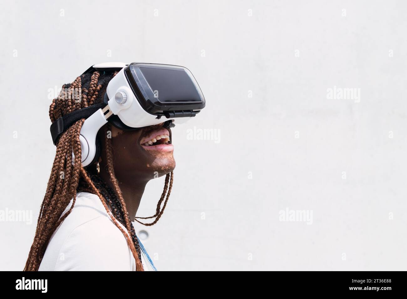 Happy woman wearing virtual reality simulators in front of wall Stock ...