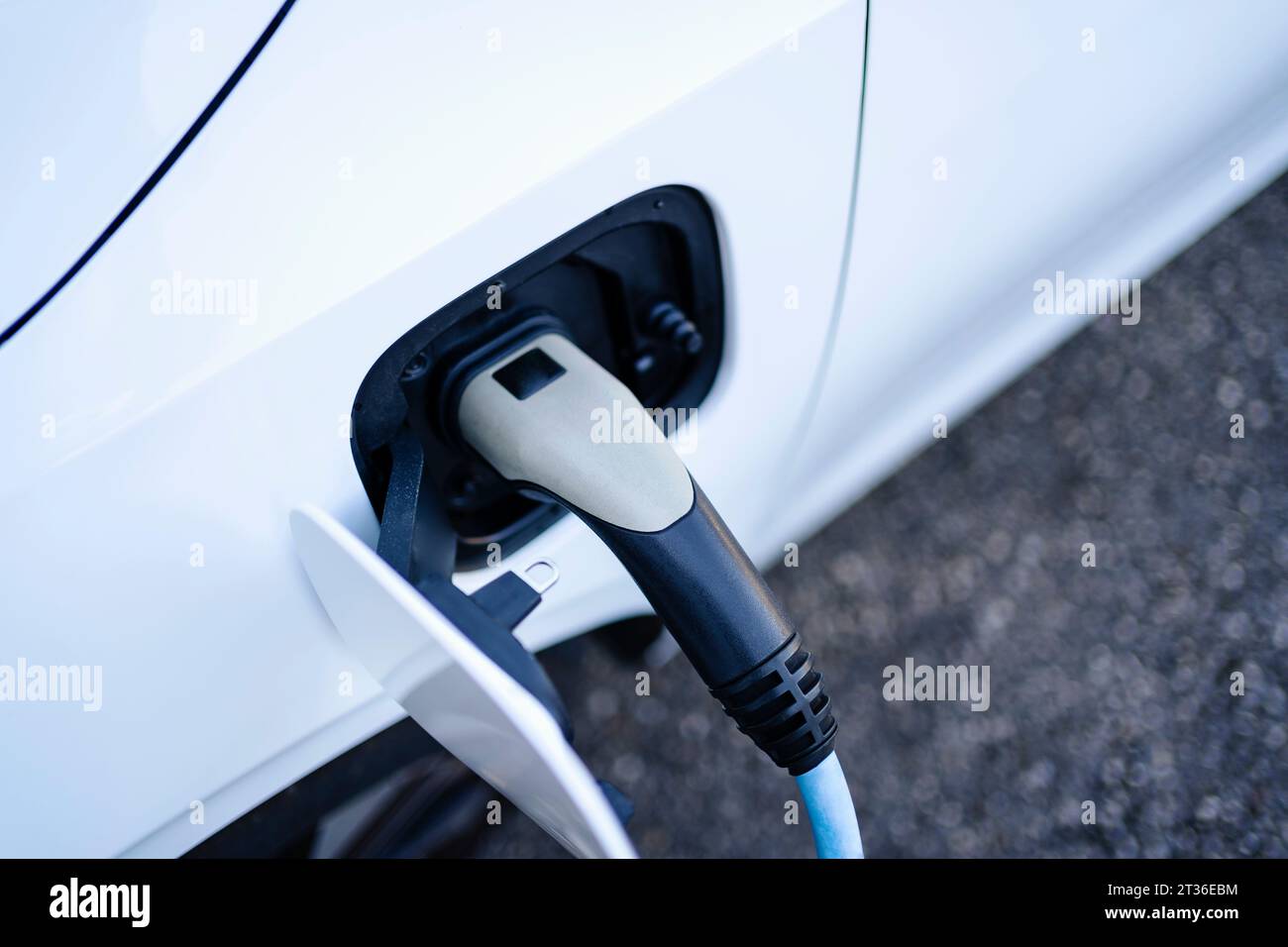 Electric car charging with plug at station Stock Photo - Alamy