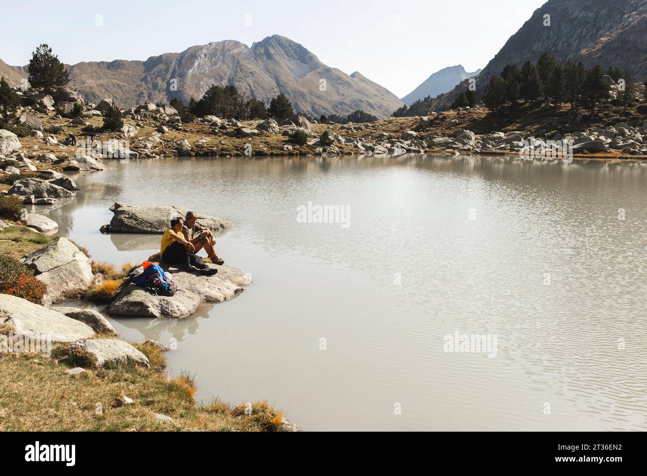 Friends sitting on rock near lake Stock Photo - Alamy
