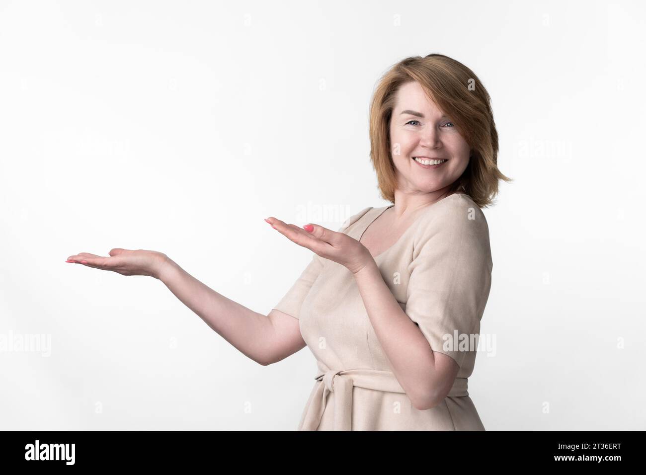 Portrait of female 49 year old in beige dress looking at camera ...