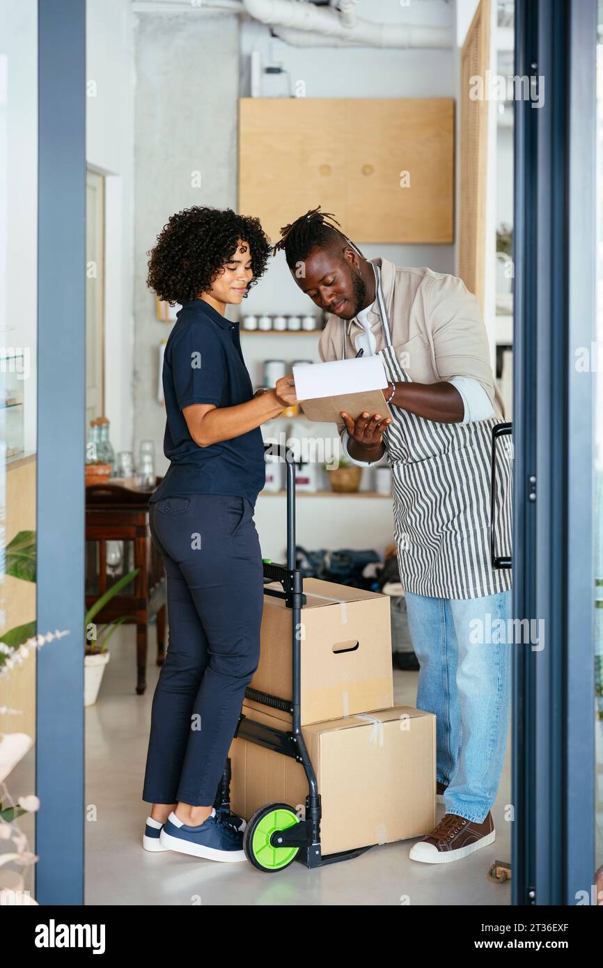 Smiling waiter and delivery woman preparing checklist in cafe Stock ...