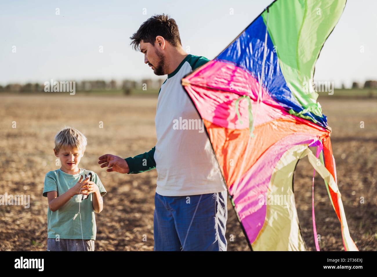 Man with multi colored kite talking to son in meadow Stock Photo - Alamy