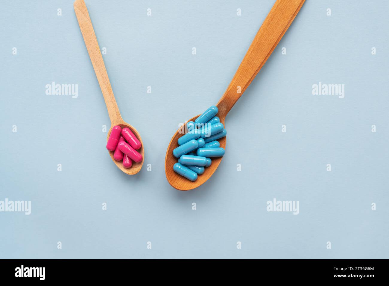 Vitamins of bright colors in wooden spoons on a blue background ...