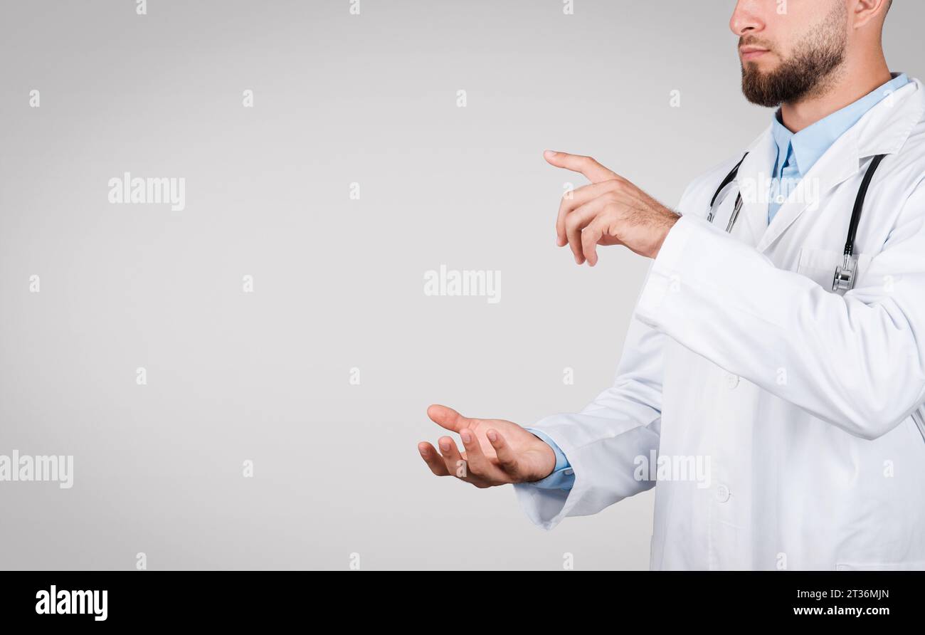 Doctor pointing at invisible object, white background, copy space Stock ...