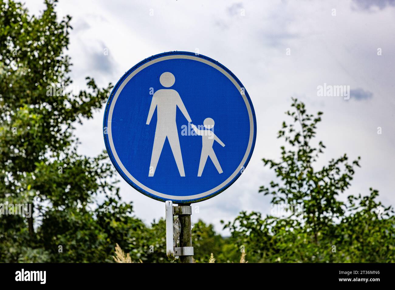 Pedestrian route or walking area sign against cloud covered sky and ...