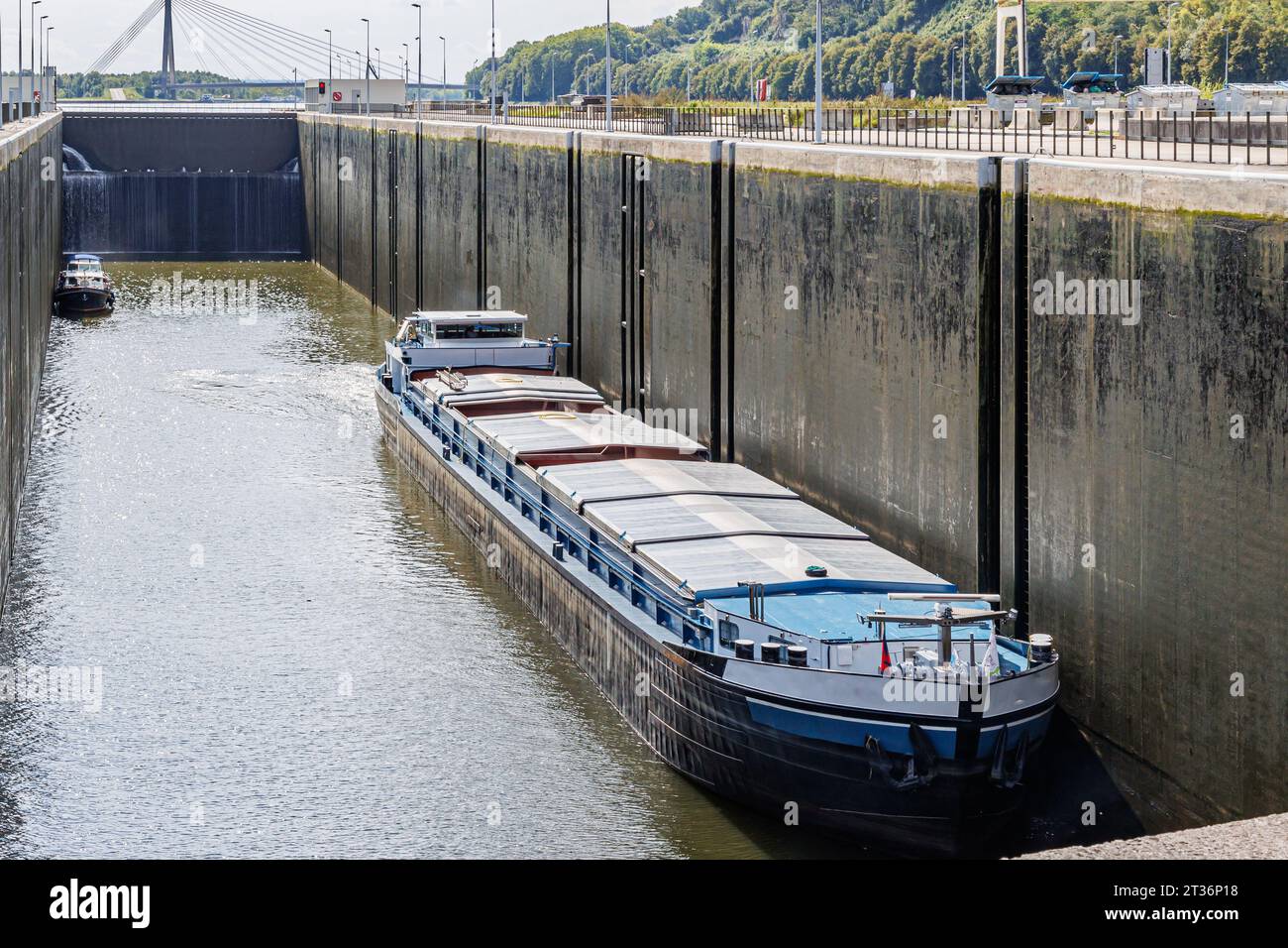 Cargo ship and small boat at Lanaye lock, between huge walls with low ...