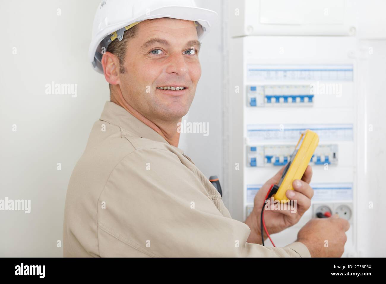 middle-aged electrician using multimeter on fusebox Stock Photo - Alamy
