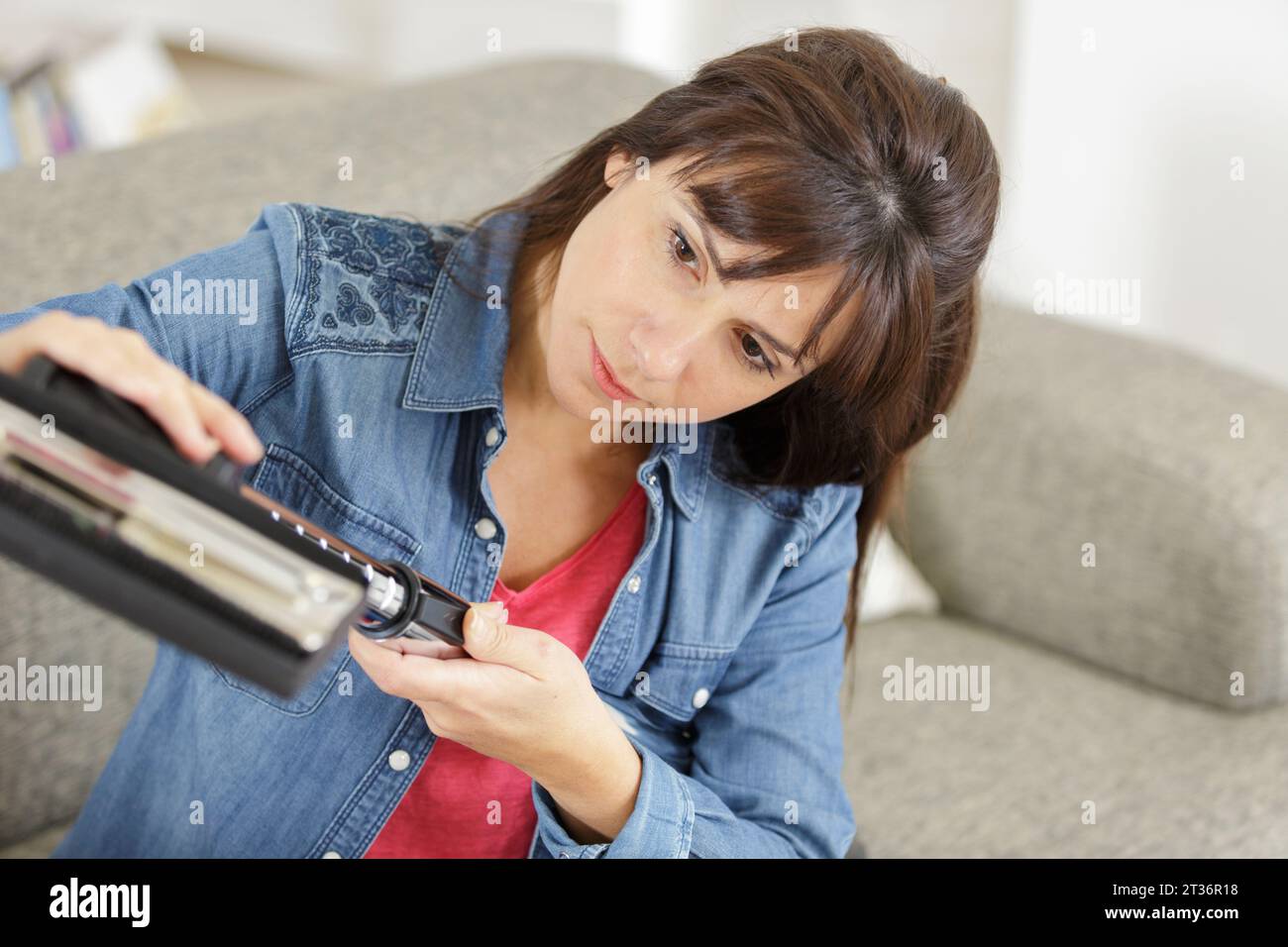 woman reluctantly cleans with vacuum cleaner Stock Photo - Alamy