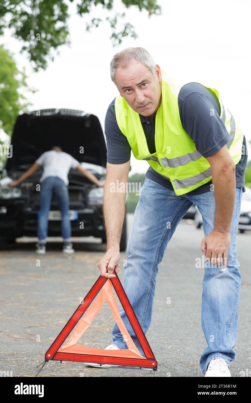 man putting danger triangle sign after vehicle breakdown Stock Photo ...