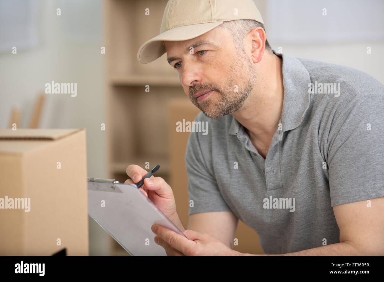 delivery man with cardboard boxes writing on clipboard Stock Photo - Alamy