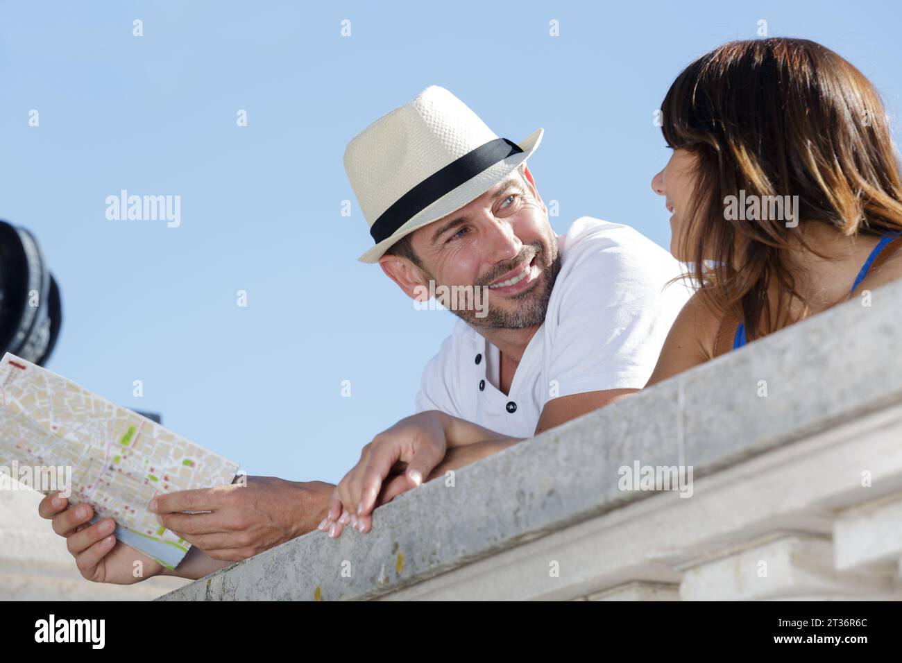 couple leaning over stone bridge looking at city map Stock Photo - Alamy