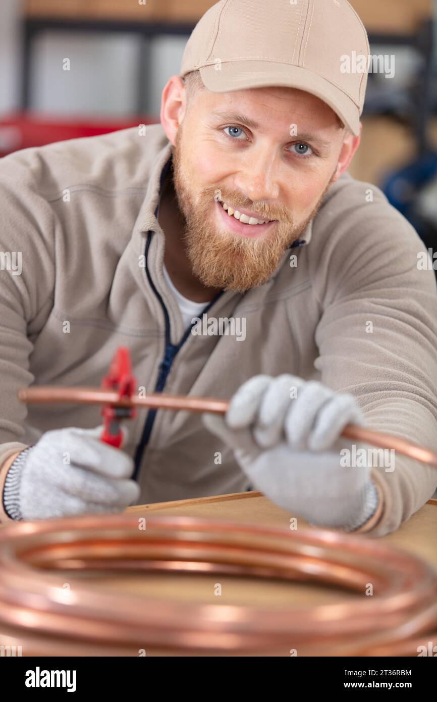 portrait of man with reel of copper pipe Stock Photo - Alamy