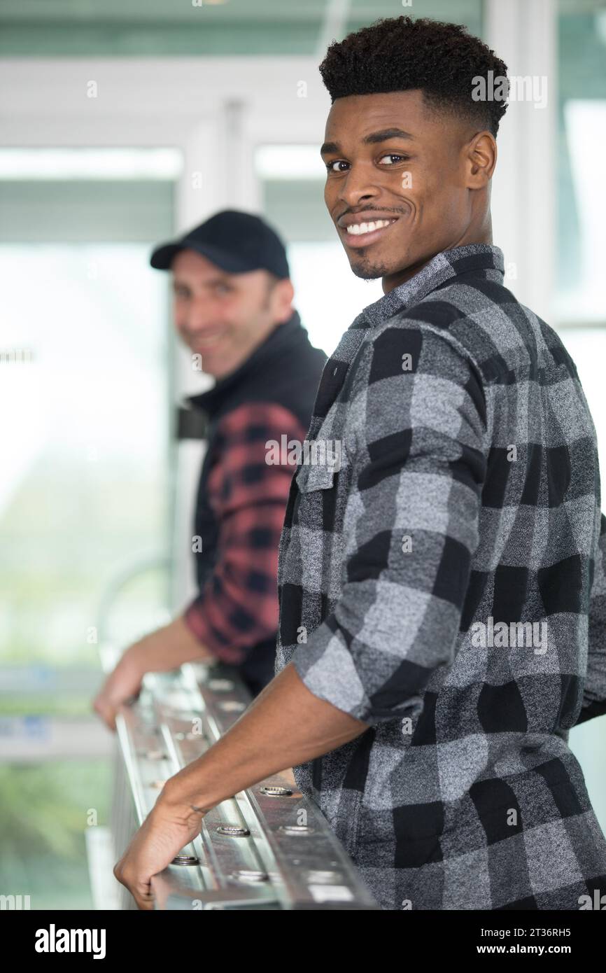 two men carrying a ladder Stock Photo - Alamy