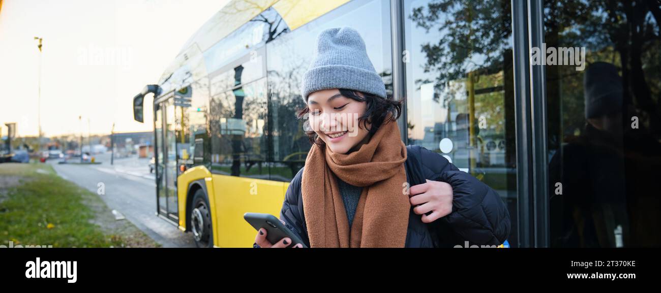 Image of girl student waiting for public transport, checks schedule on ...
