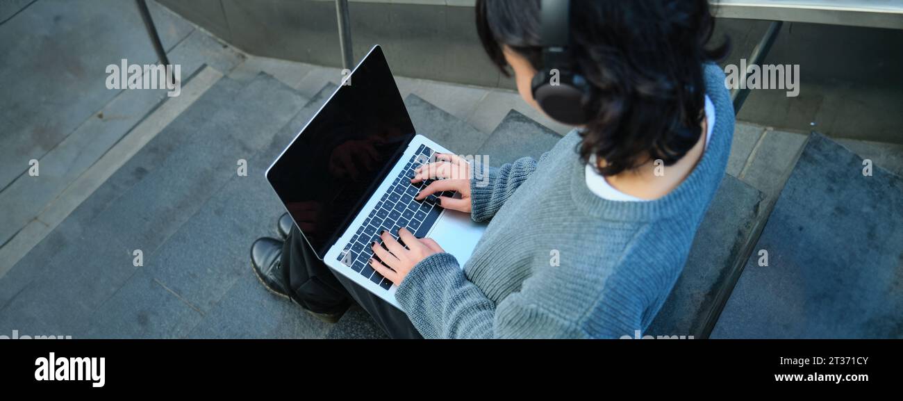 Close up portrait of girl, student works on laptop and listens music in ...
