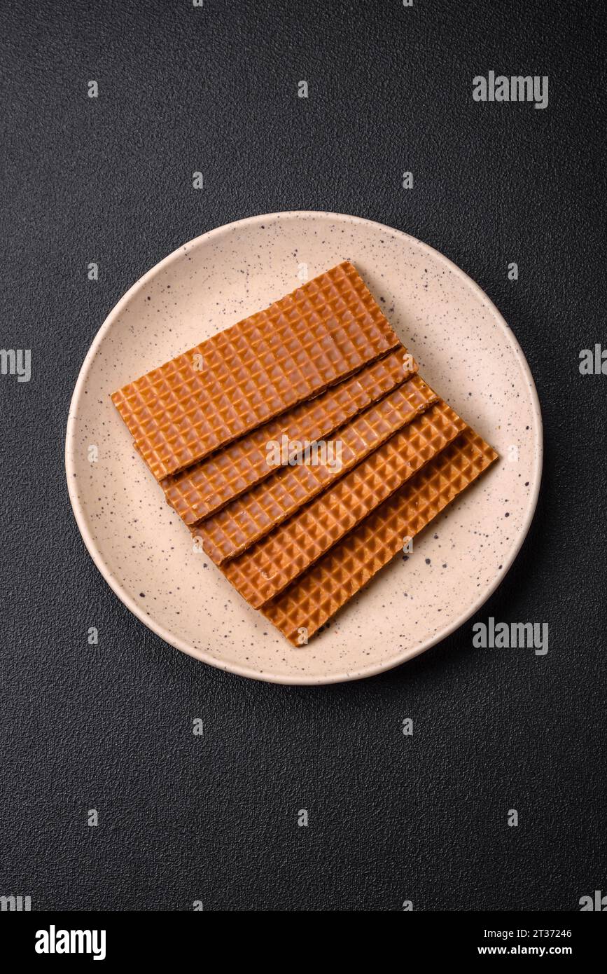 Delicious sweet crispy rectangular waffles on a ceramic plate on a dark ...