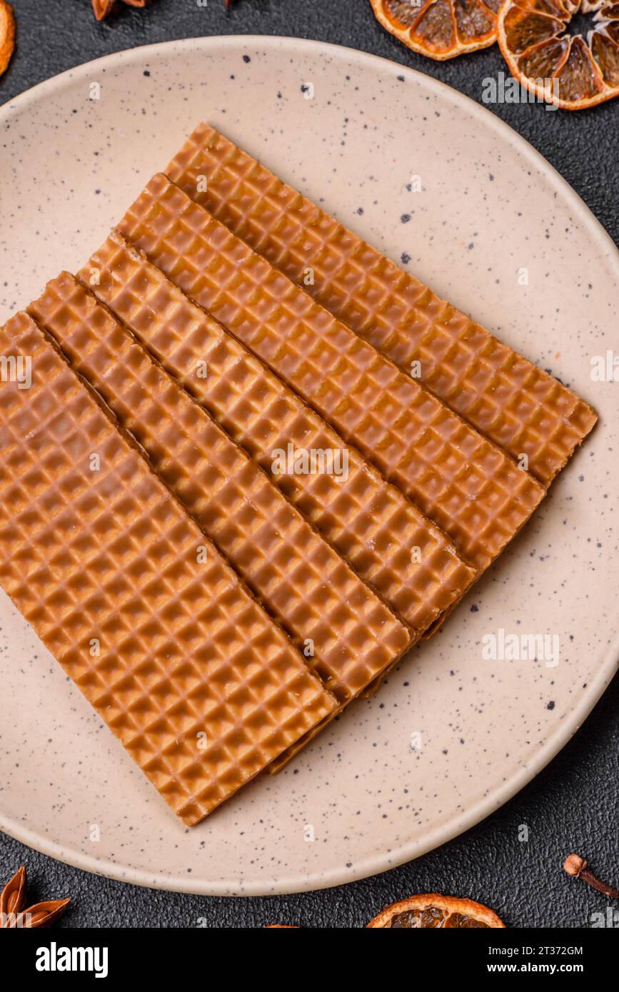 Delicious sweet crispy rectangular waffles on a ceramic plate on a dark ...