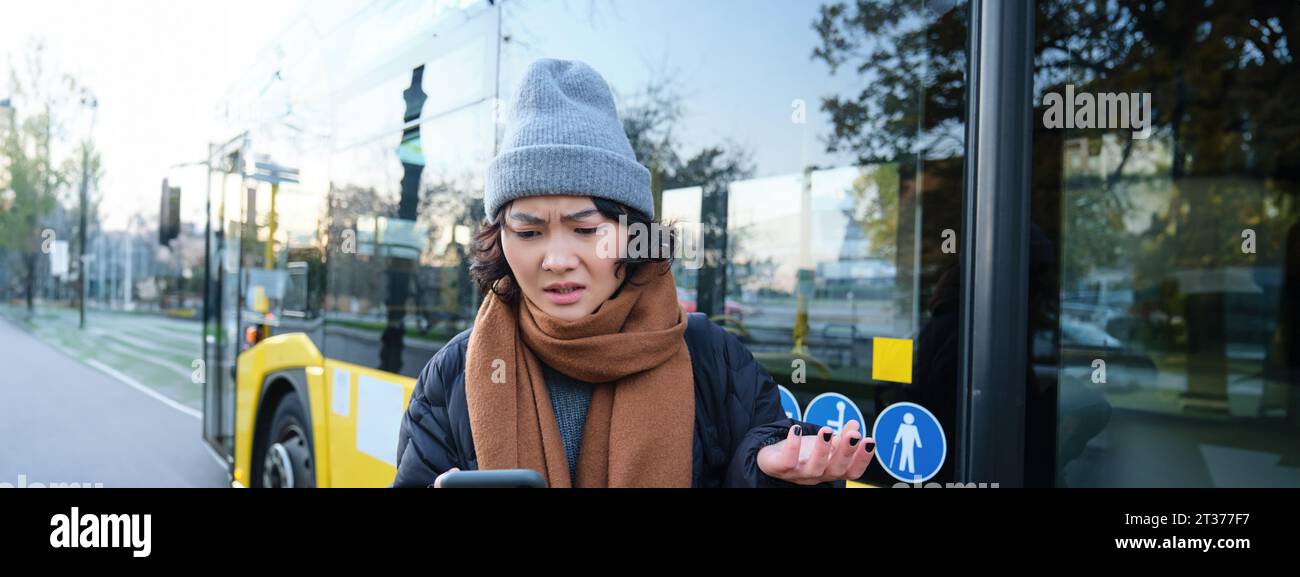 Portrait of confused young woman, looking at her smartphone app with ...