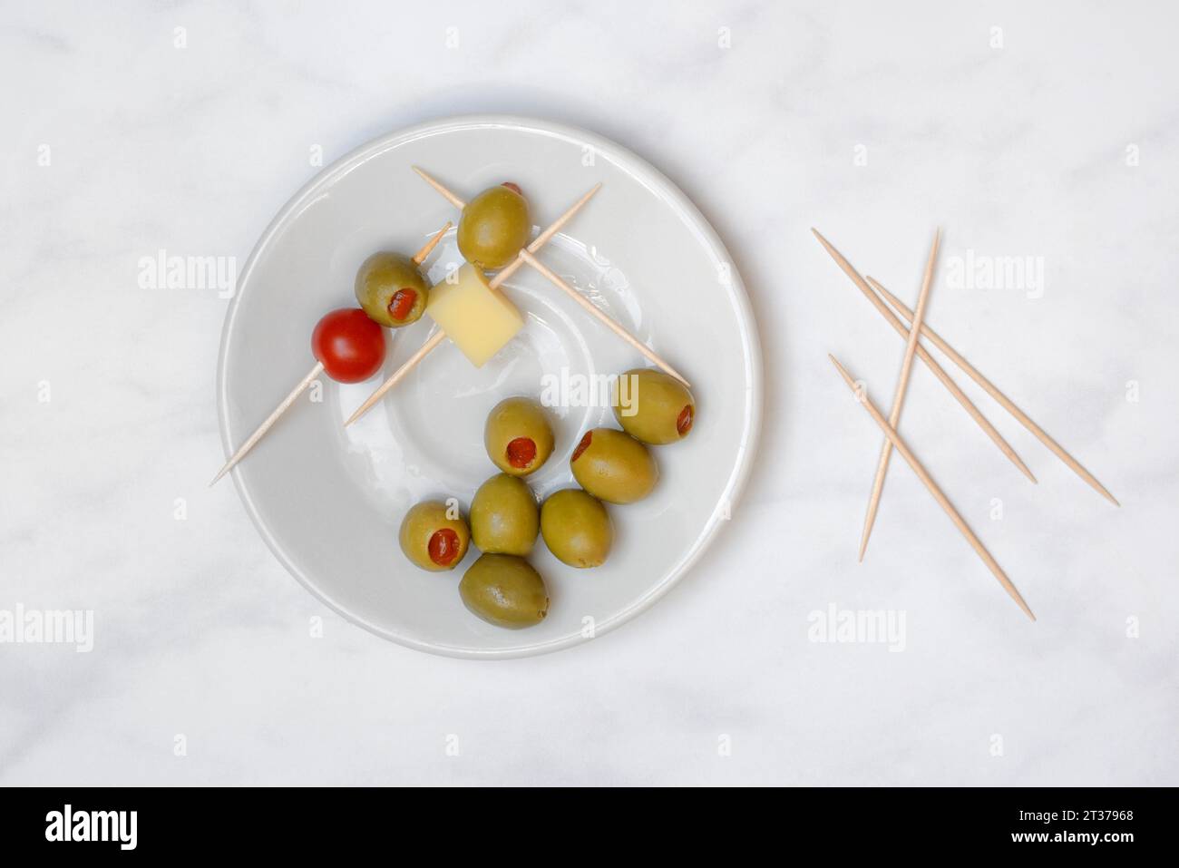 Stuffed olives on plate with cheese cubes and tomato, toothpick Stock ...