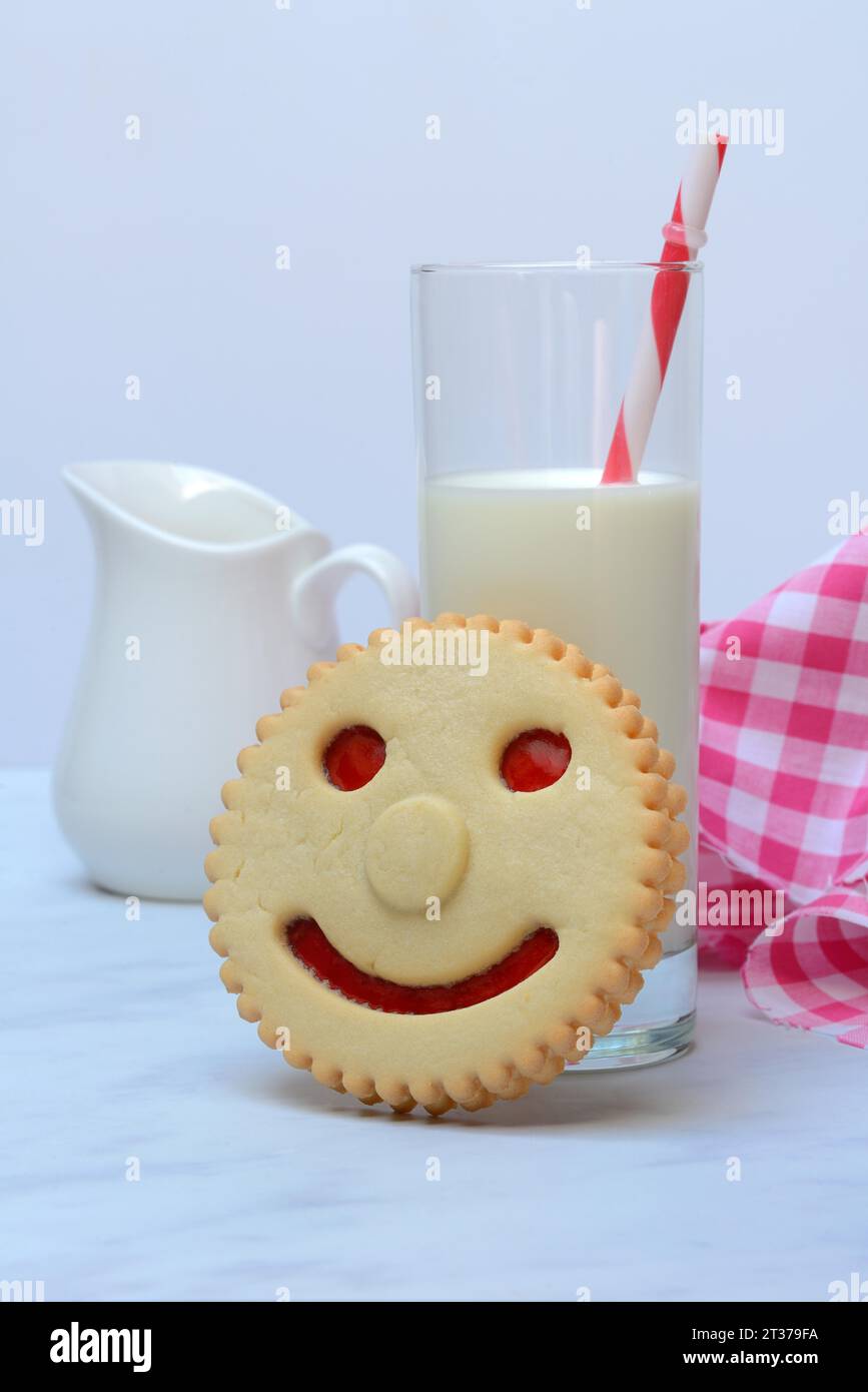 Pastry with smiley face and glass of milk Stock Photo - Alamy