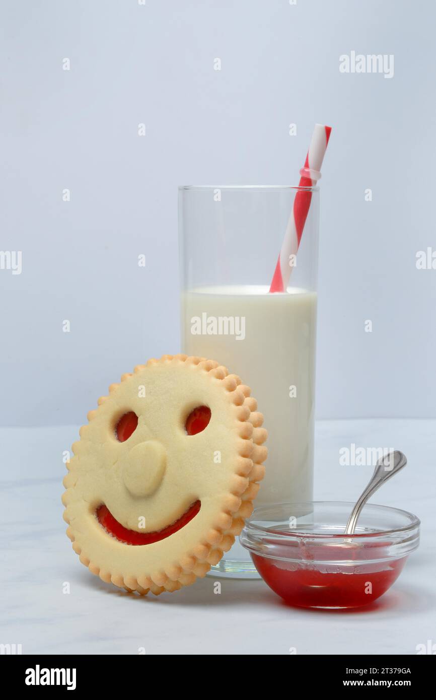 Pastry with smiley face and glass of milk Stock Photo - Alamy