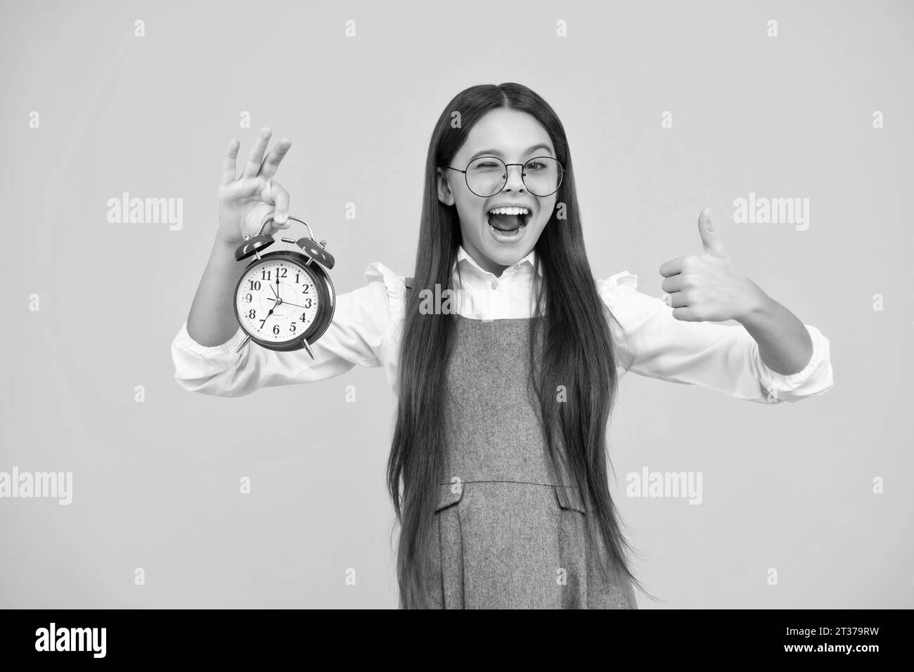 Teen student girl hold clock isolated on yellow background. Time to ...